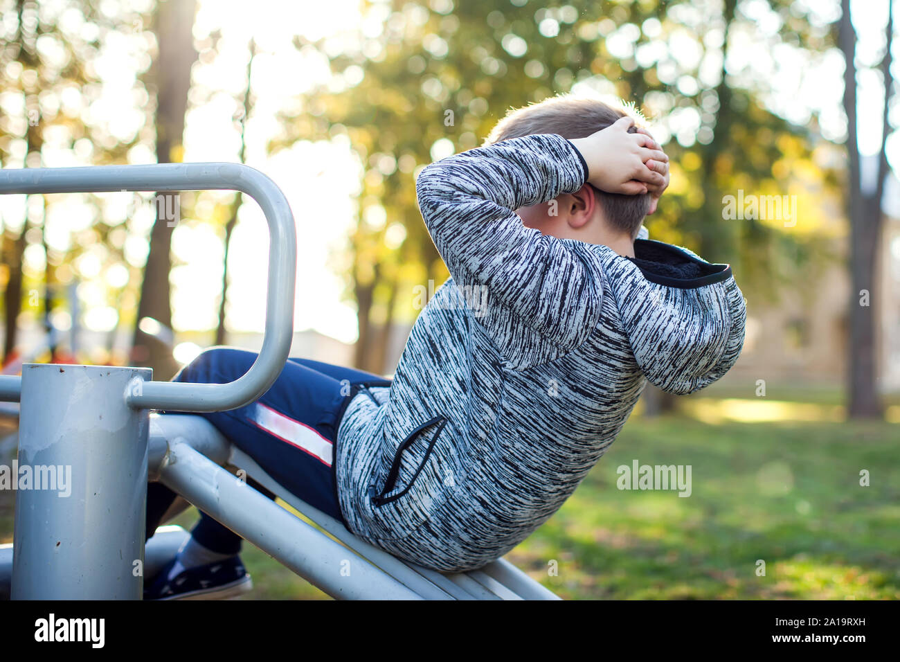 Kid boy does workout on trainer equipment outdoor. Children, activity ...