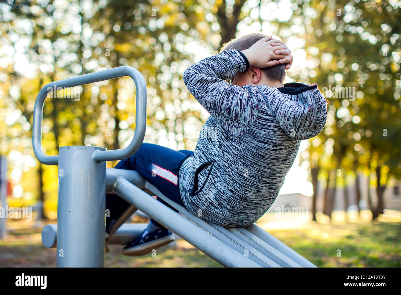 Kid boy does workout on trainer equipment outdoor. Children, activity ...