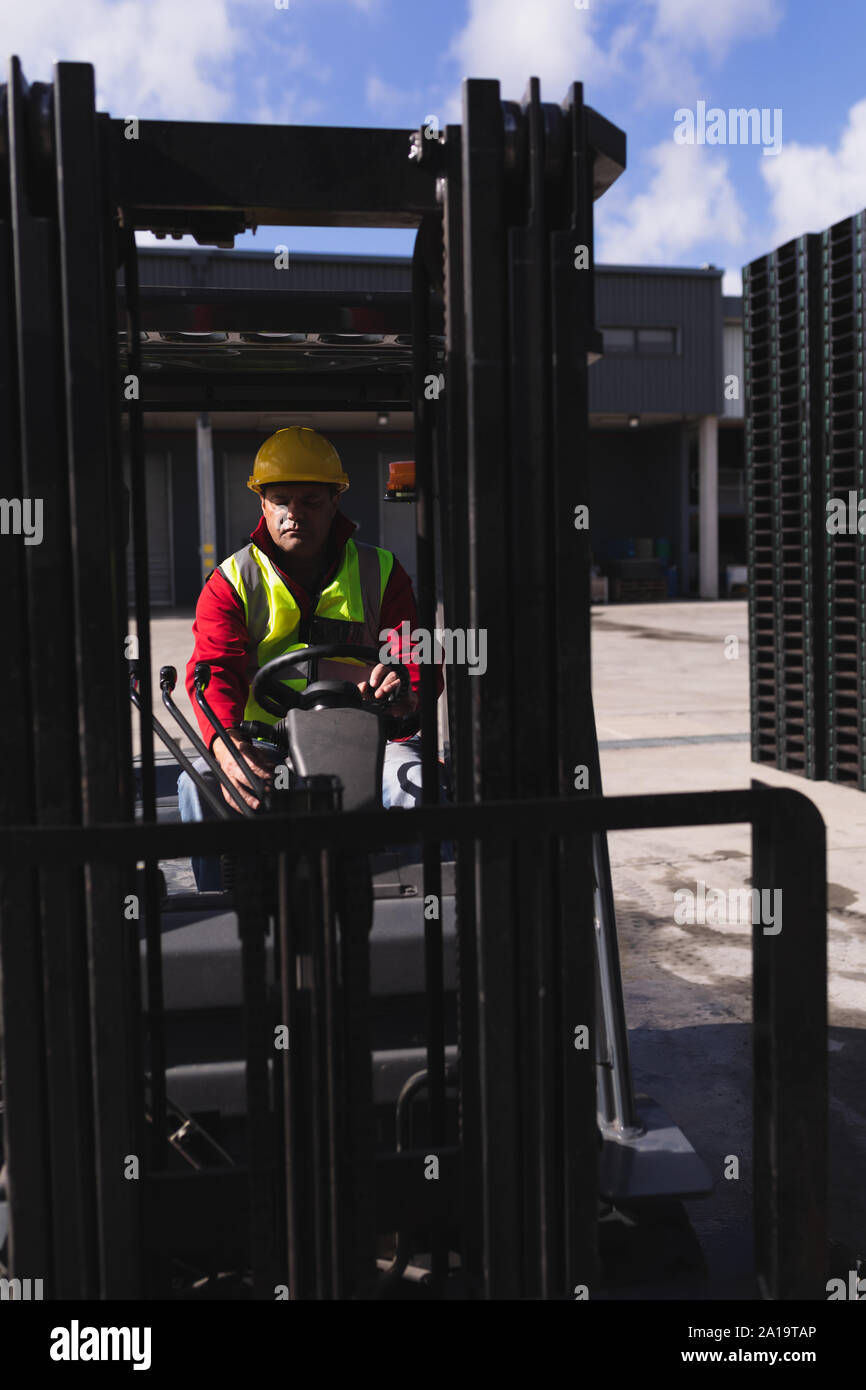 Factory worker driving a forklift truck outside a factory warehouse ...