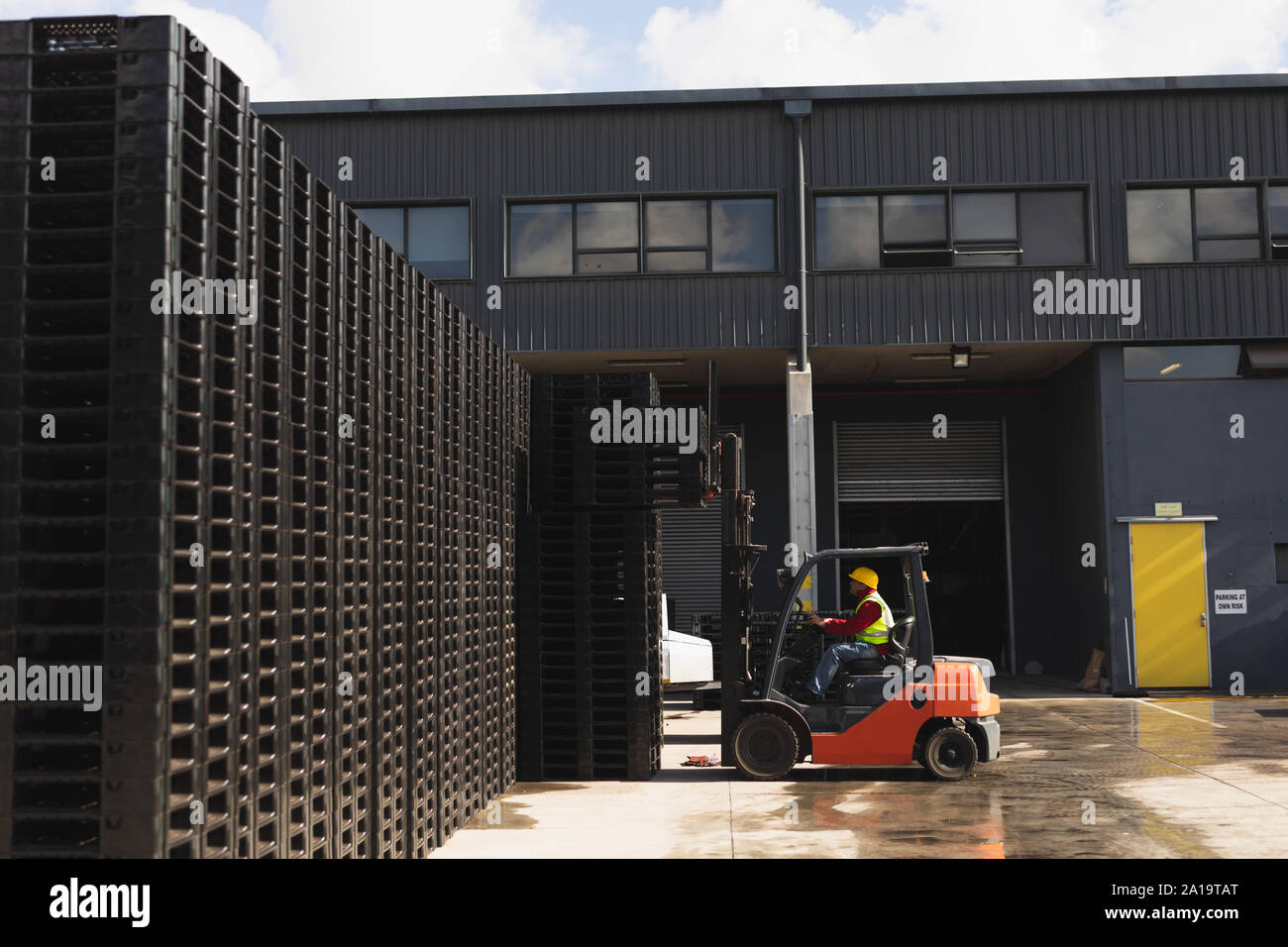 Factory worker driving a forklift truck outside a factory warehouse ...