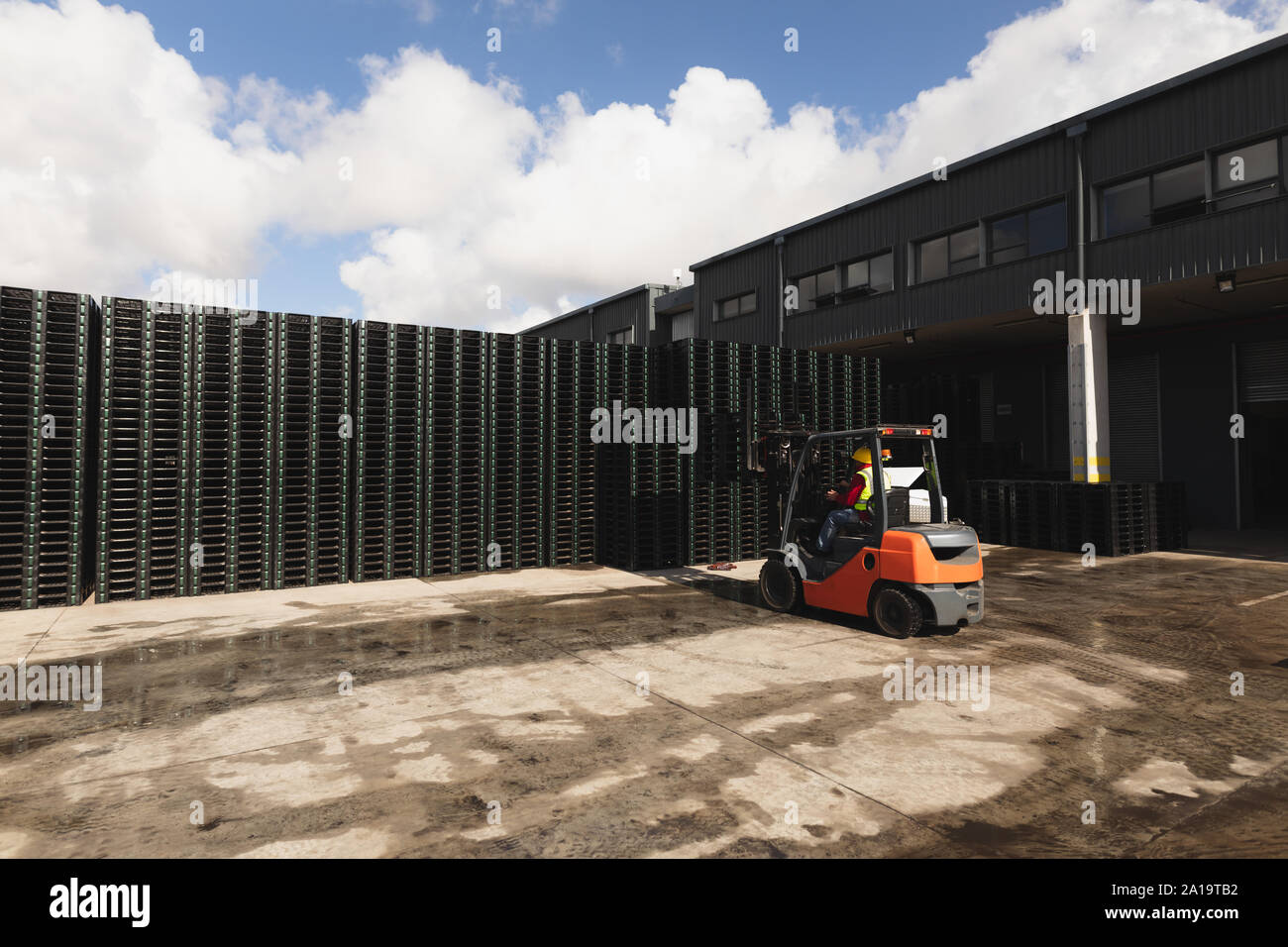Factory worker driving a forklift truck outside a factory warehouse ...
