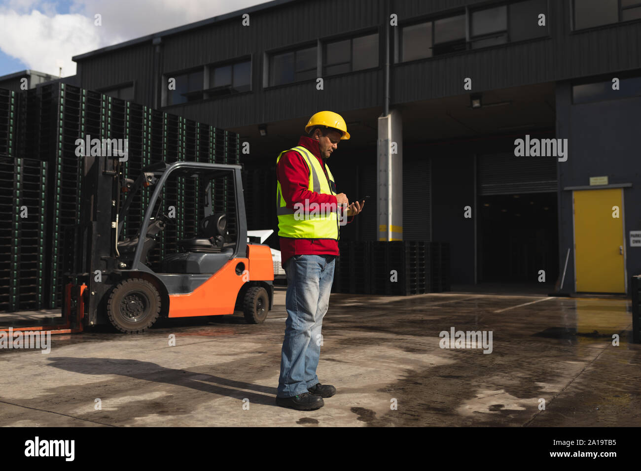 Forklift driver using smartphone outside factory warehouse Stock Photo ...