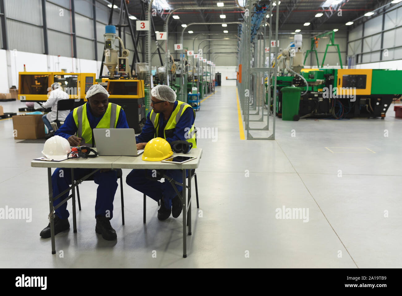Male factory workers using laptop in a factory warehouse Stock Photo ...