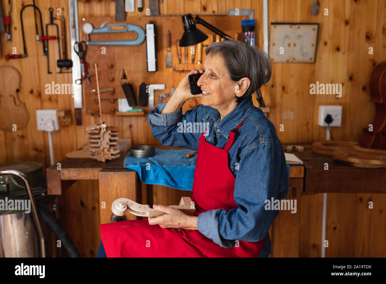 Female luthier talking on the phone in a workshop Stock Photo - Alamy