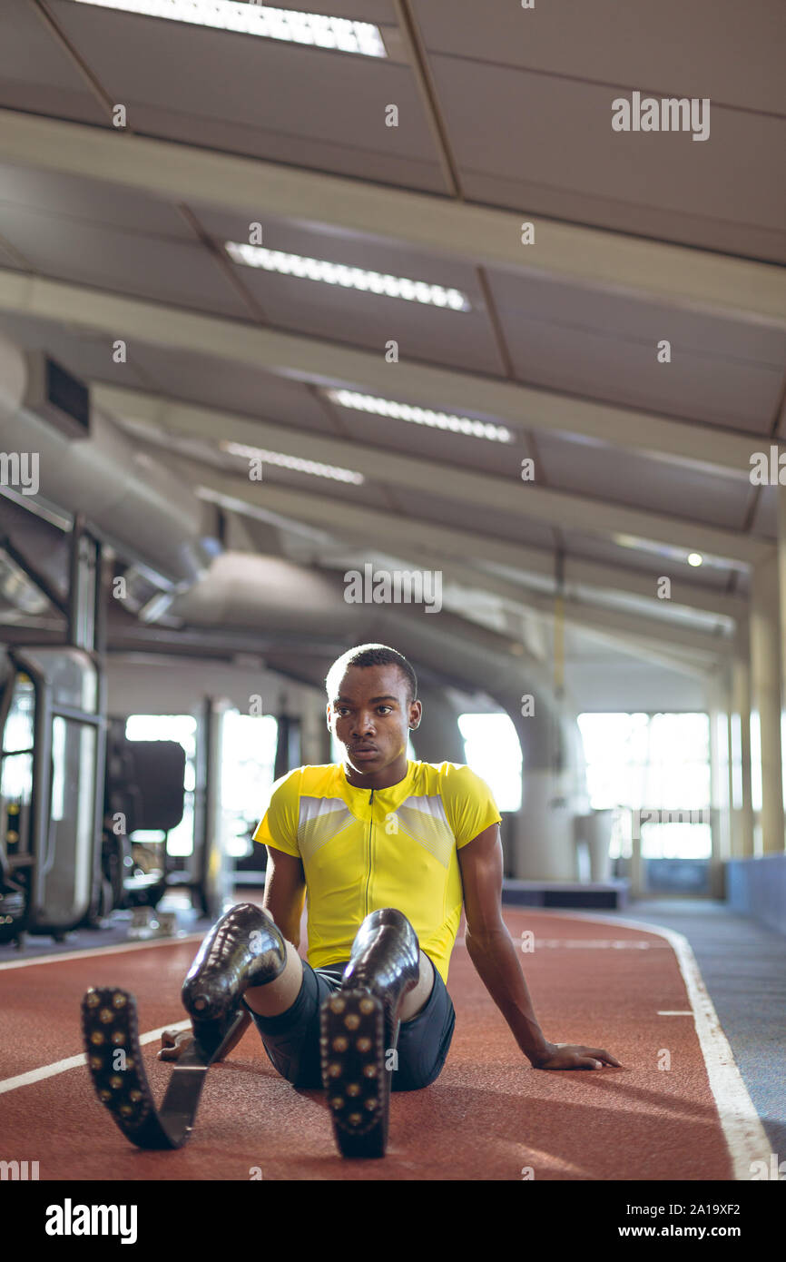 Disabled male athletic relaxing on a running track in fitness center ...