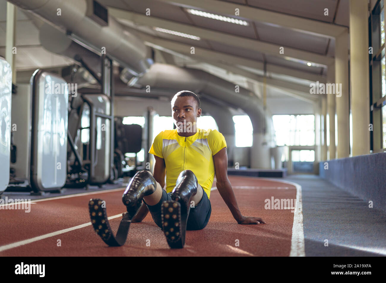 Disabled male athletic relaxing on a running track in fitness center ...