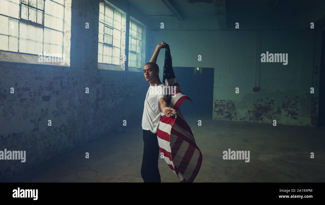 Young man holding an American flag inside an empty warehouse Stock ...