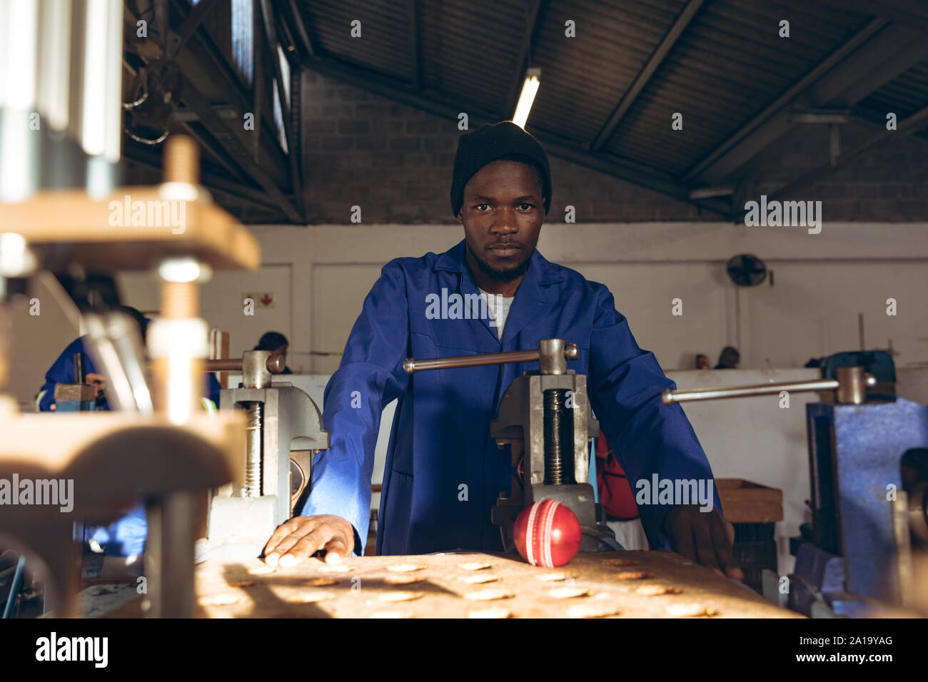 Young man working in a cricket ball factory Stock Photo - Alamy