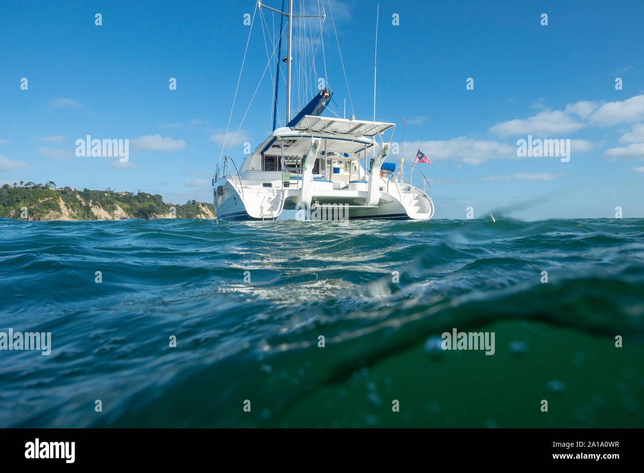 Leopard Catamaran anchored close to shore, stern viewed from water line ...