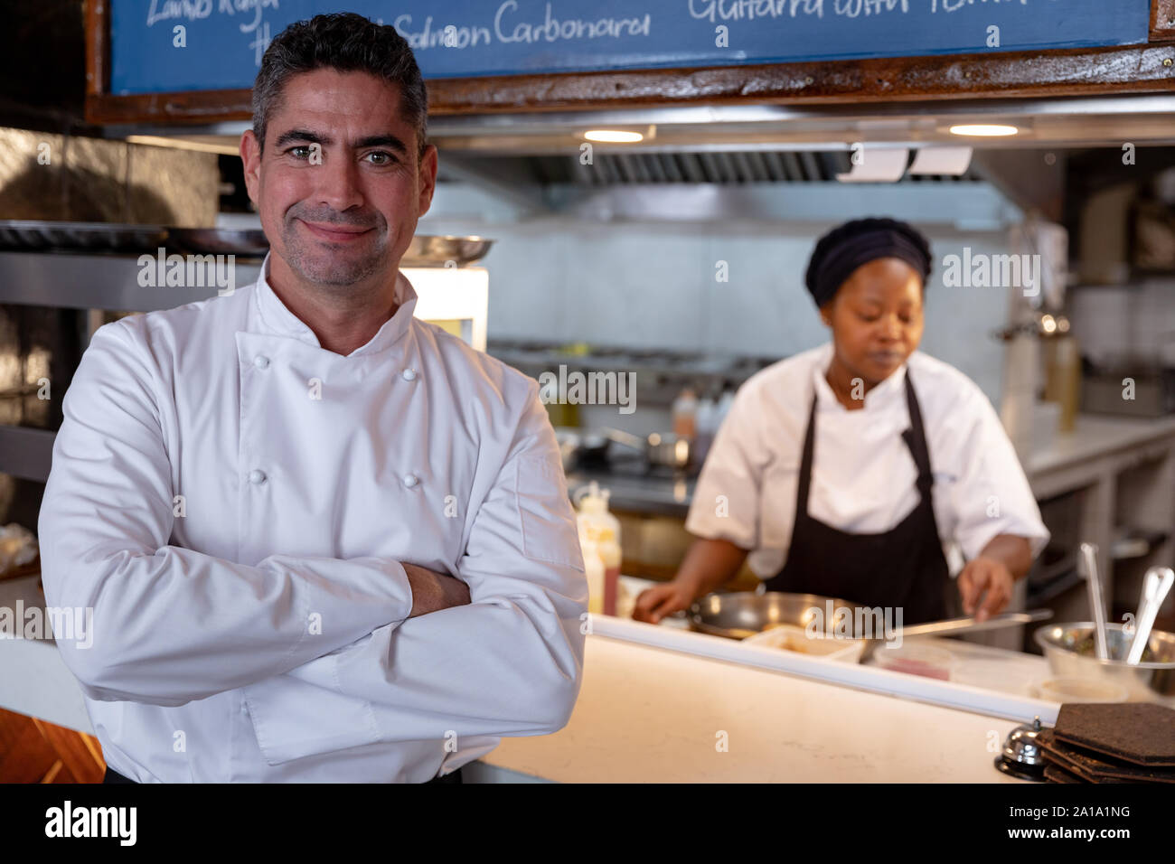 Chef standing in kitchen with crossed arms Stock Photo - Alamy