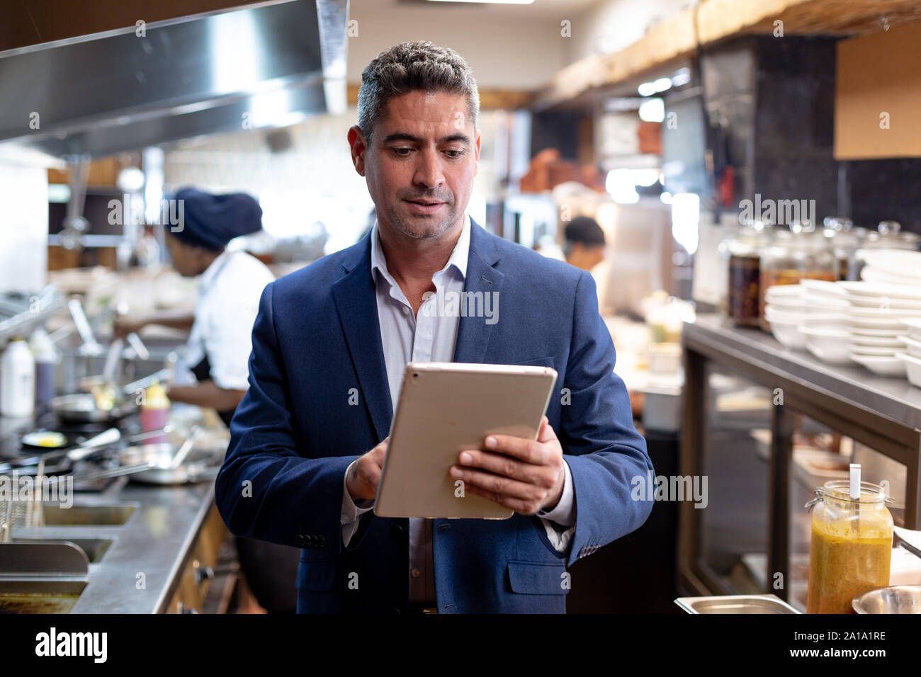 Restaurant manager using a tablet in a kitchen Stock Photo - Alamy
