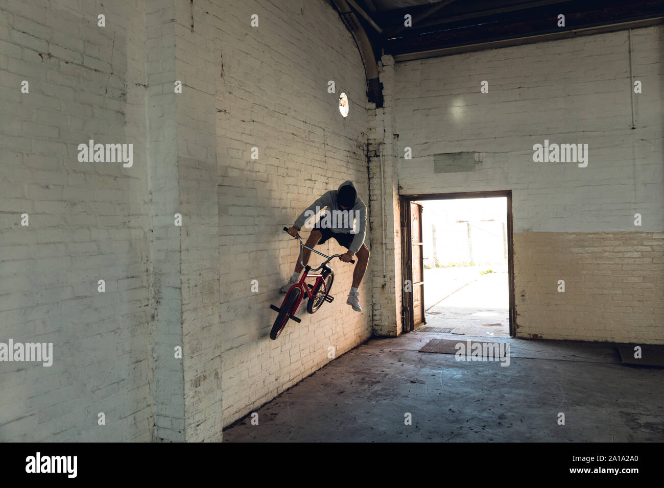 BMX rider riding on the wall in an empty warehouse Stock Photo - Alamy