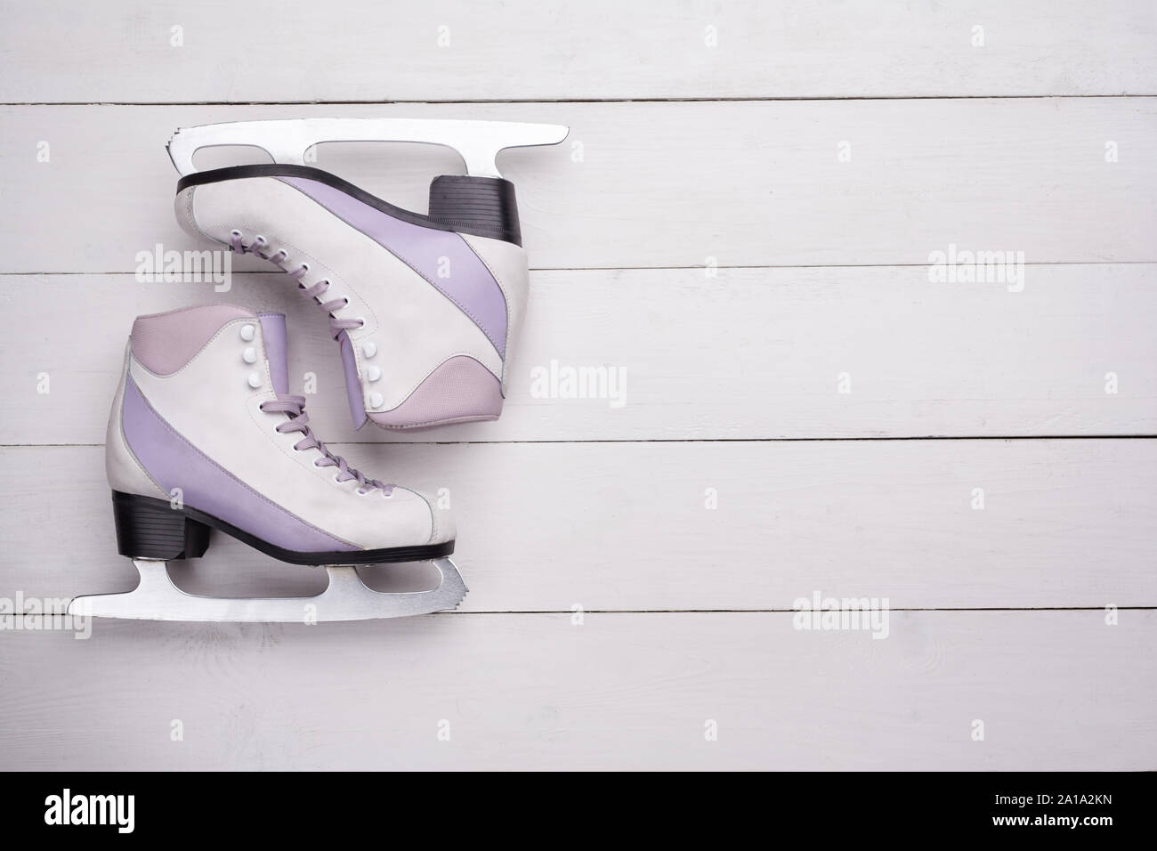 Close-up photo of professional ice skates lying on a white wooden ...