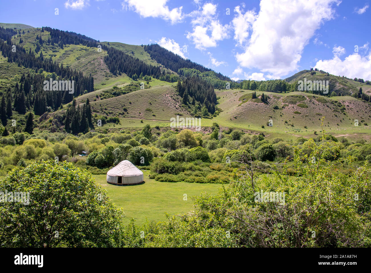White yurt on jailoo against the background of mountains covered by ...