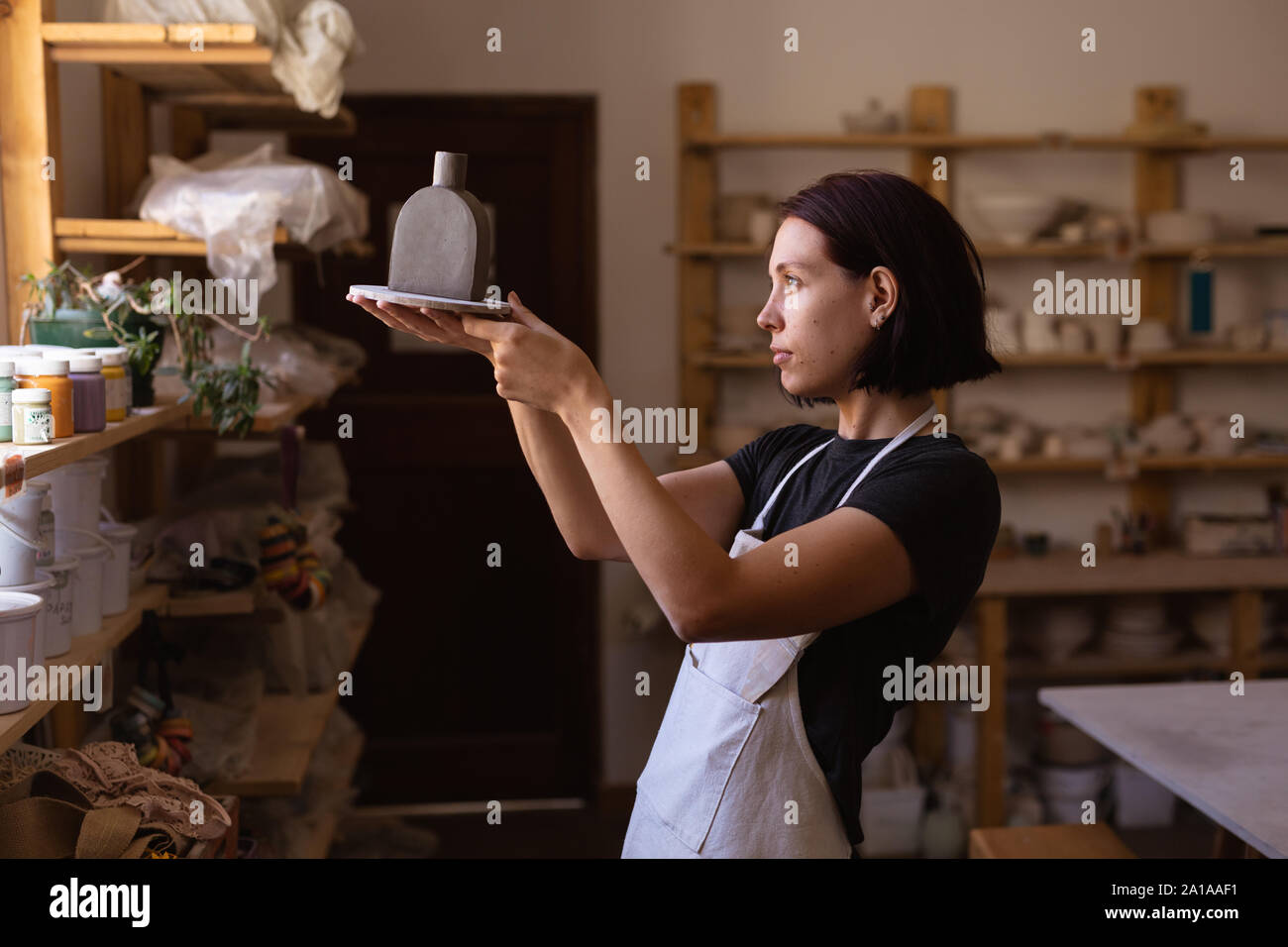 Female potter in a pottery studio holding a flask Stock Photo - Alamy