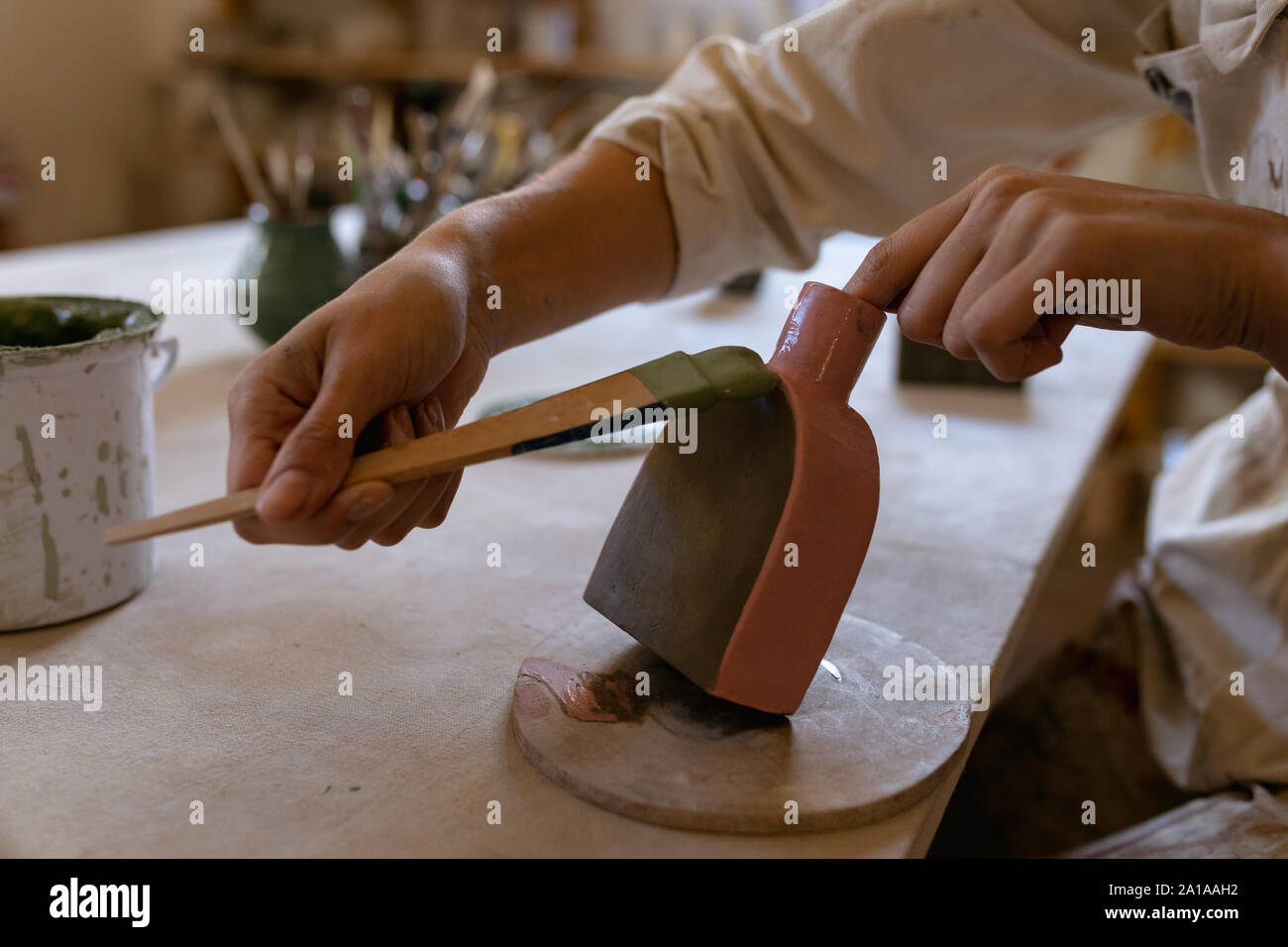 Female potter in a pottery studio painting clay flask Stock Photo - Alamy
