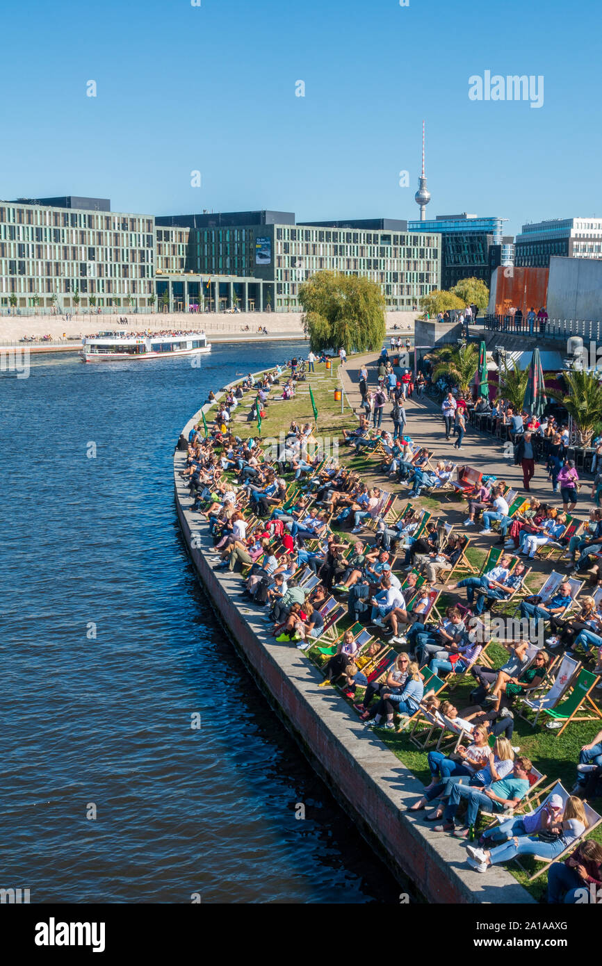 People sunbathing on deckchairs by Spree river on Capital Beach in ...