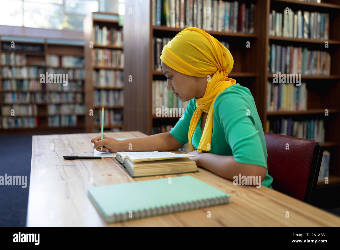 Young woman studying in library Stock Photo - Alamy