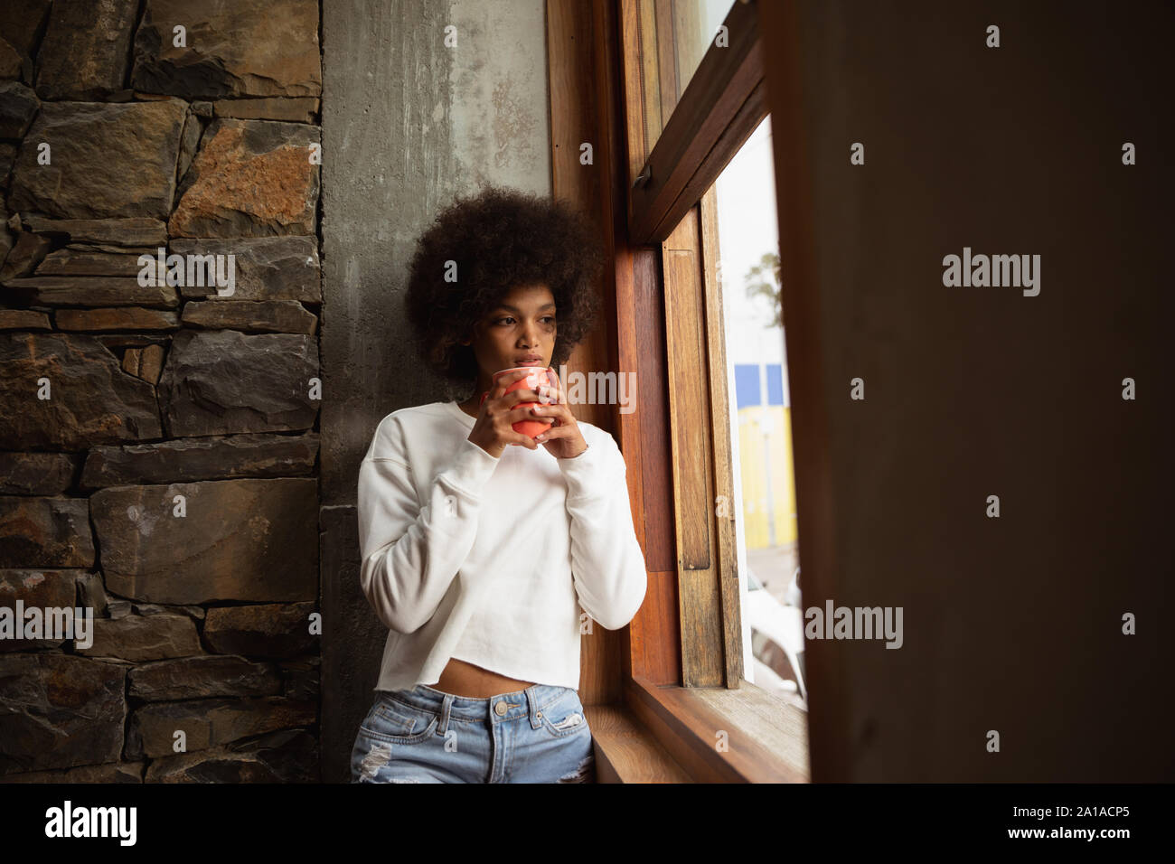 Young woman drinking coffee by a window Stock Photo - Alamy