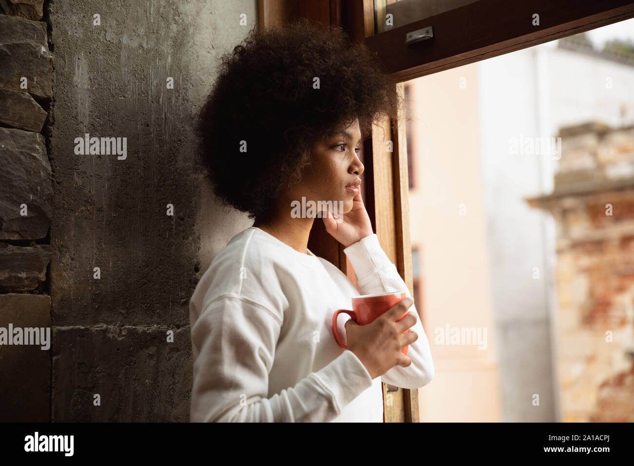 Young woman drinking coffee by a window Stock Photo - Alamy