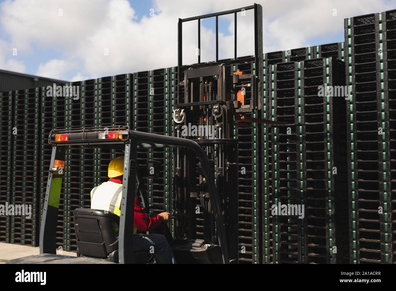 Factory worker driving a forklift truck outside a factory warehouse ...