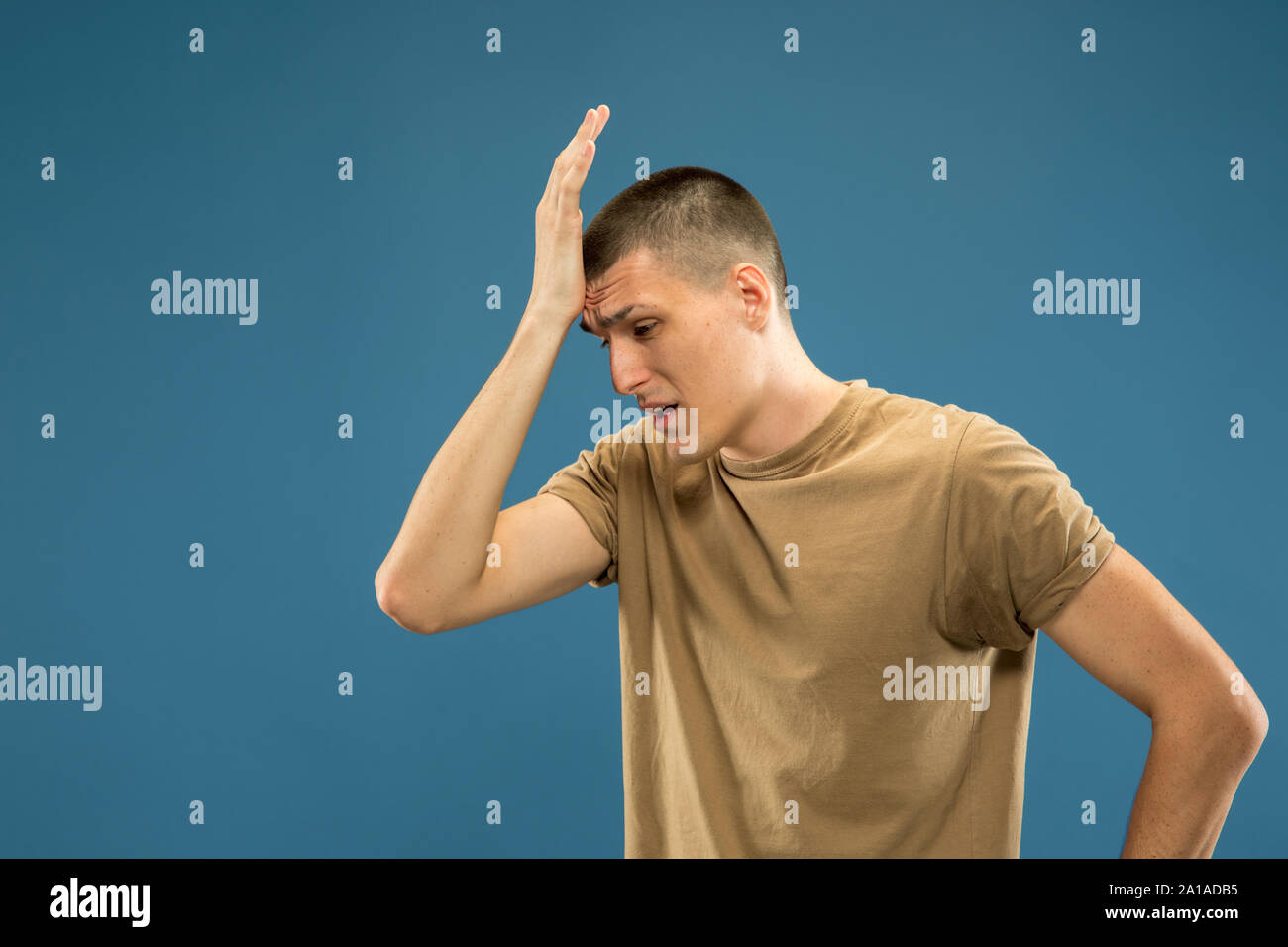 Caucasian young man's half-length portrait on blue studio background ...