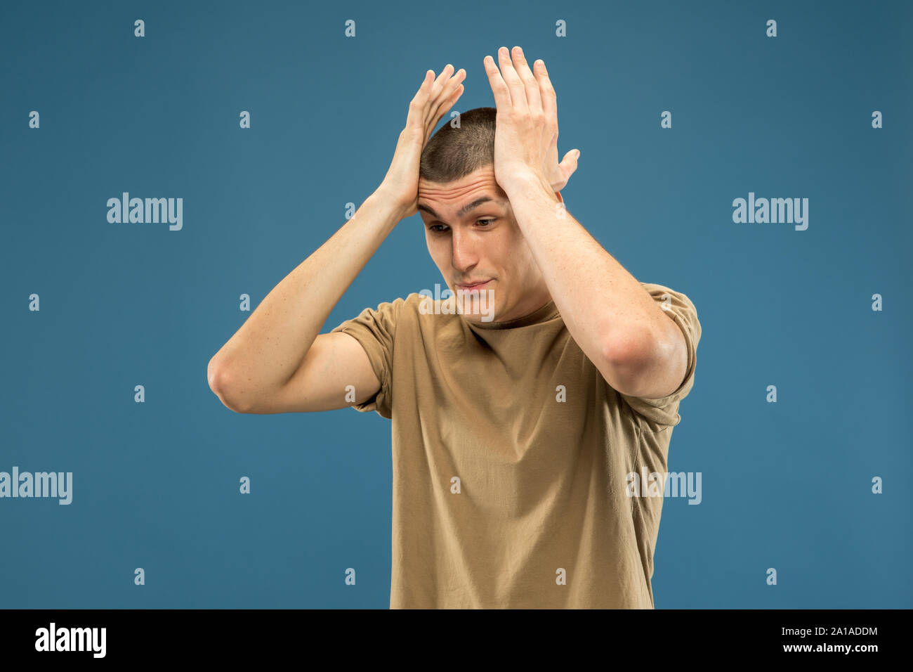 Caucasian young man's half-length portrait on blue studio background ...