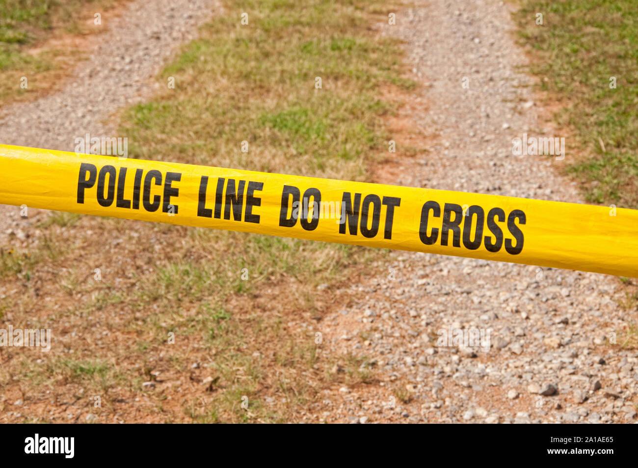 Police line do not cross - warning tape across rural gravel roadway ...