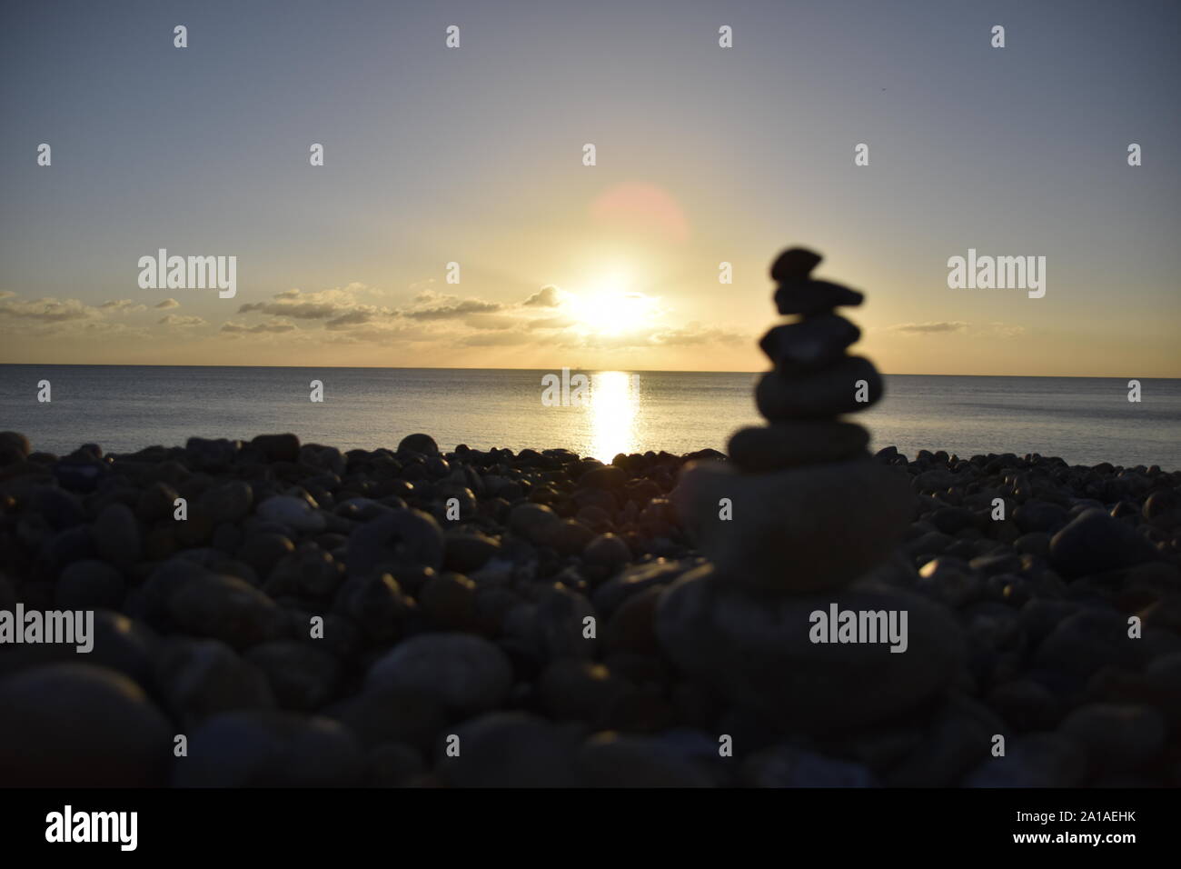 Pile of stones on beach in front of sunset Stock Photo - Alamy