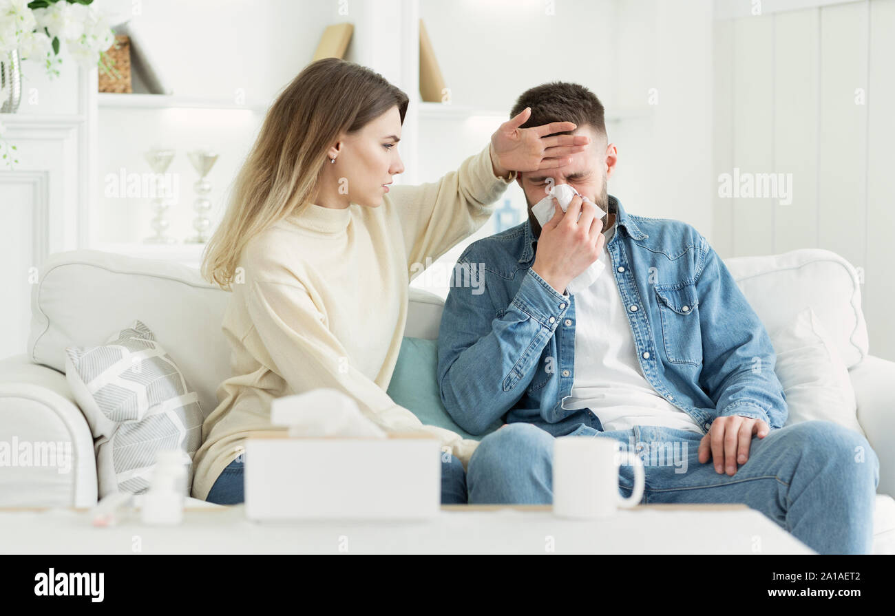 Take care. Woman touching forehead of ill husband Stock Photo - Alamy