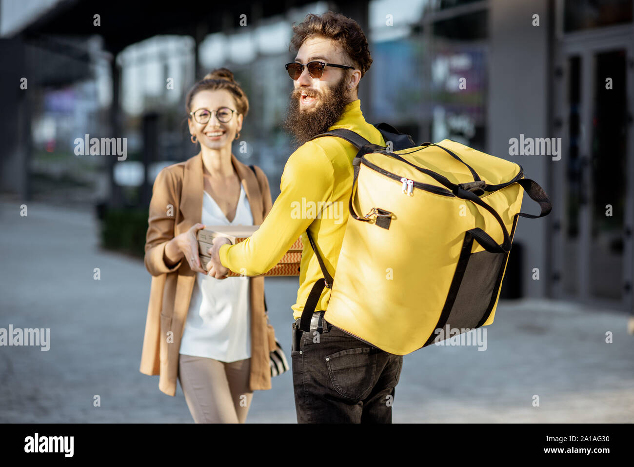 Portrait of a happy courier delivering pizza to a young woman client ...
