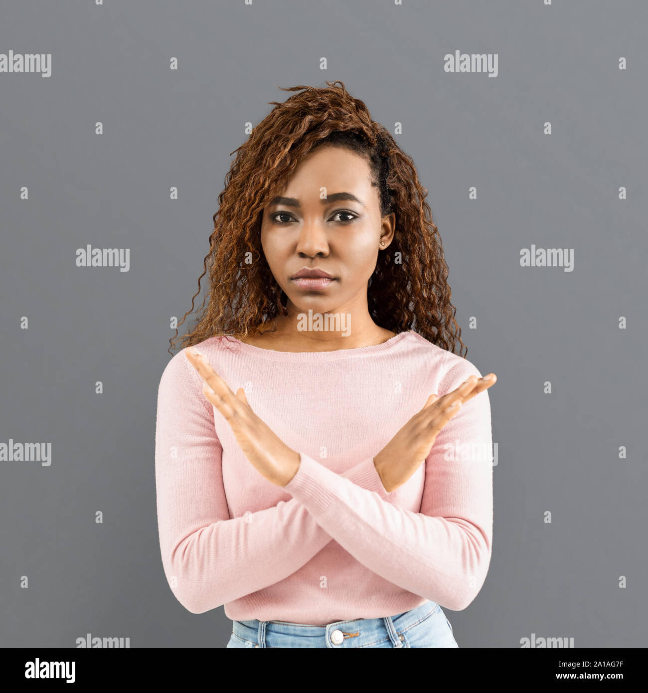 Young serious woman showing stop sign with arms crossed Stock Photo - Alamy