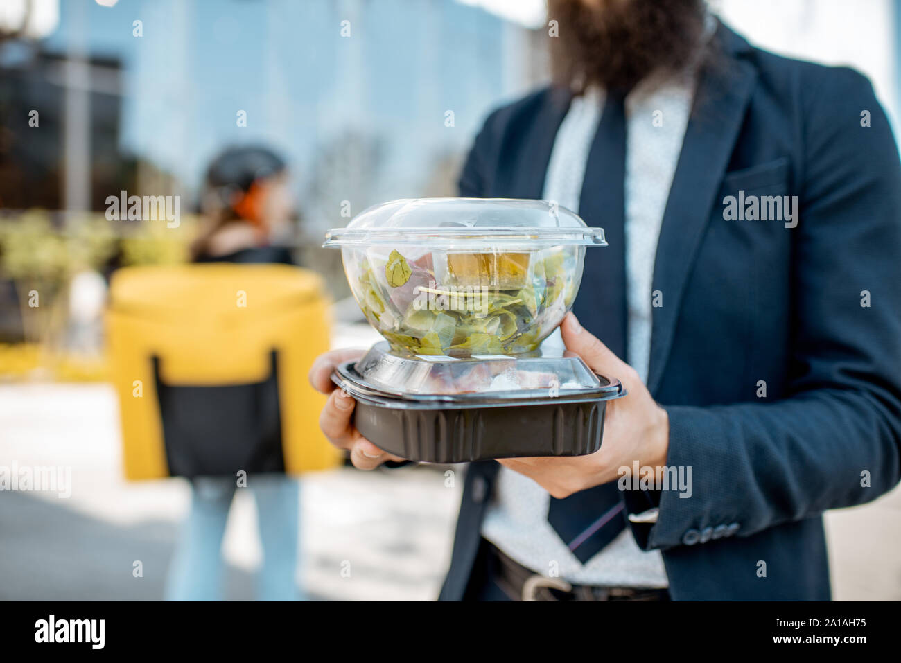 Businessman holding lunch boxes with takeaway food received from a ...