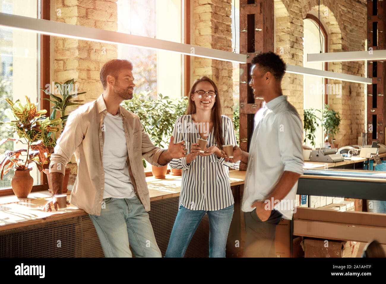 Nice coffee break. Three young and cheerful colleagues in casual wear ...