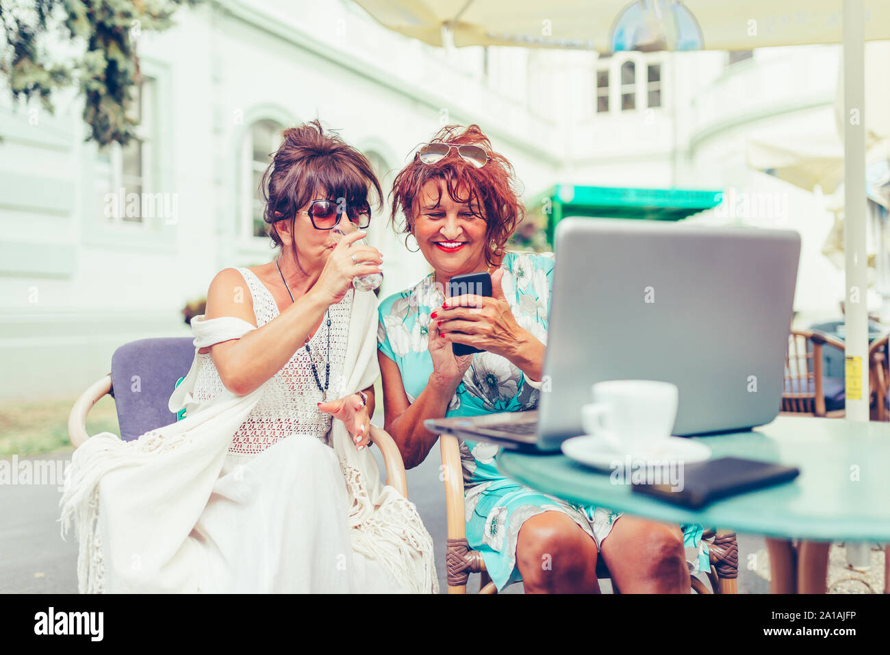 Two Happy Senior Women Friends Sharing Social Media In A Smart Phone