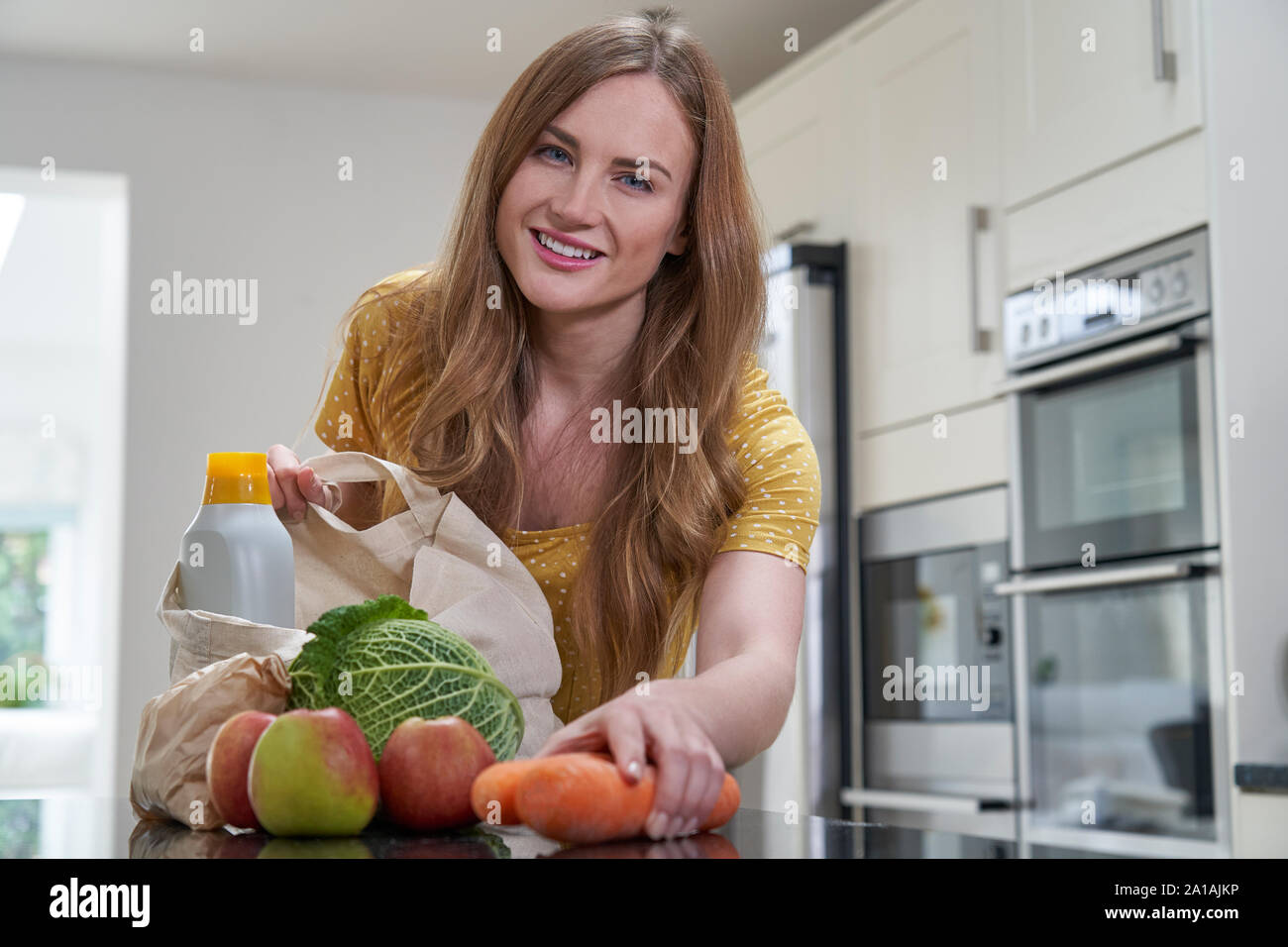 Portrait Of Woman Returning Home From Shopping Trip Unpacking Plastic ...