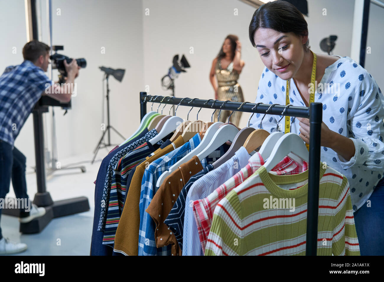 Stylist Choosing Clothes For Fashion To Wear On Photo Shoot In Studio ...
