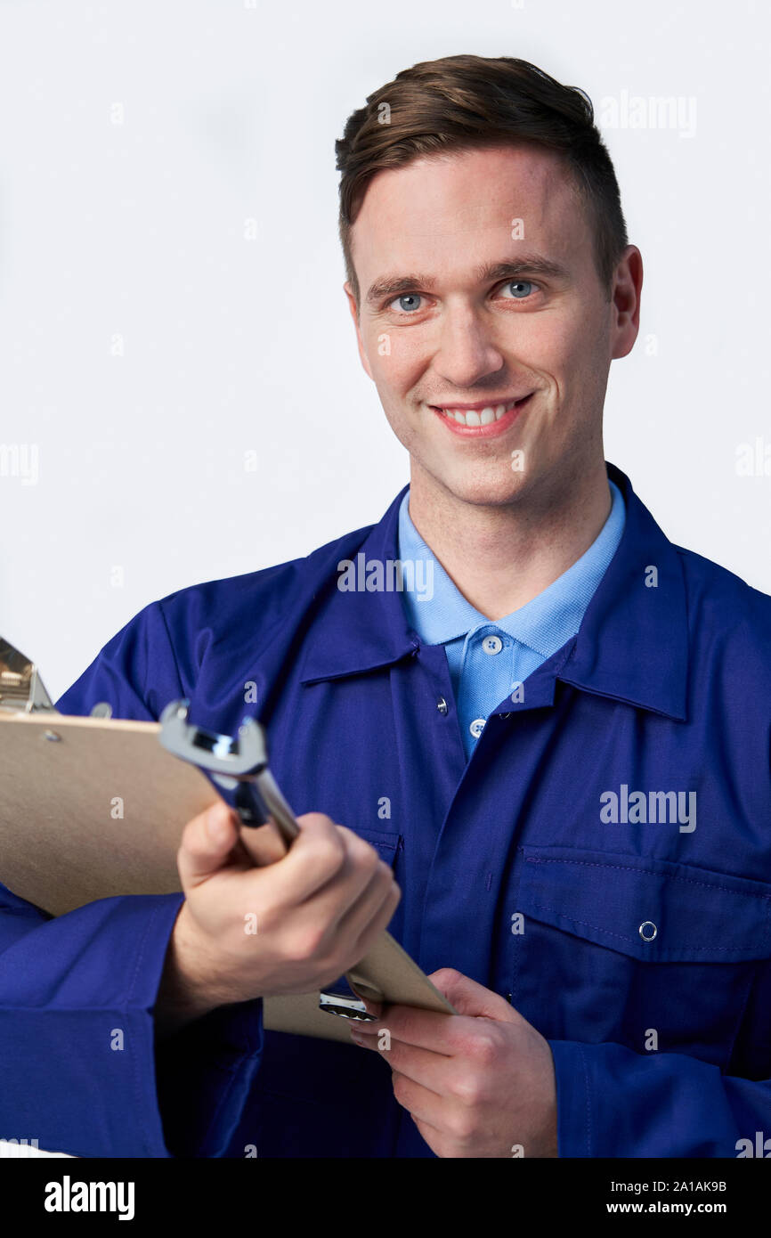 Studio Portrait Of Male Engineer With Clipboard And Spanner Against ...