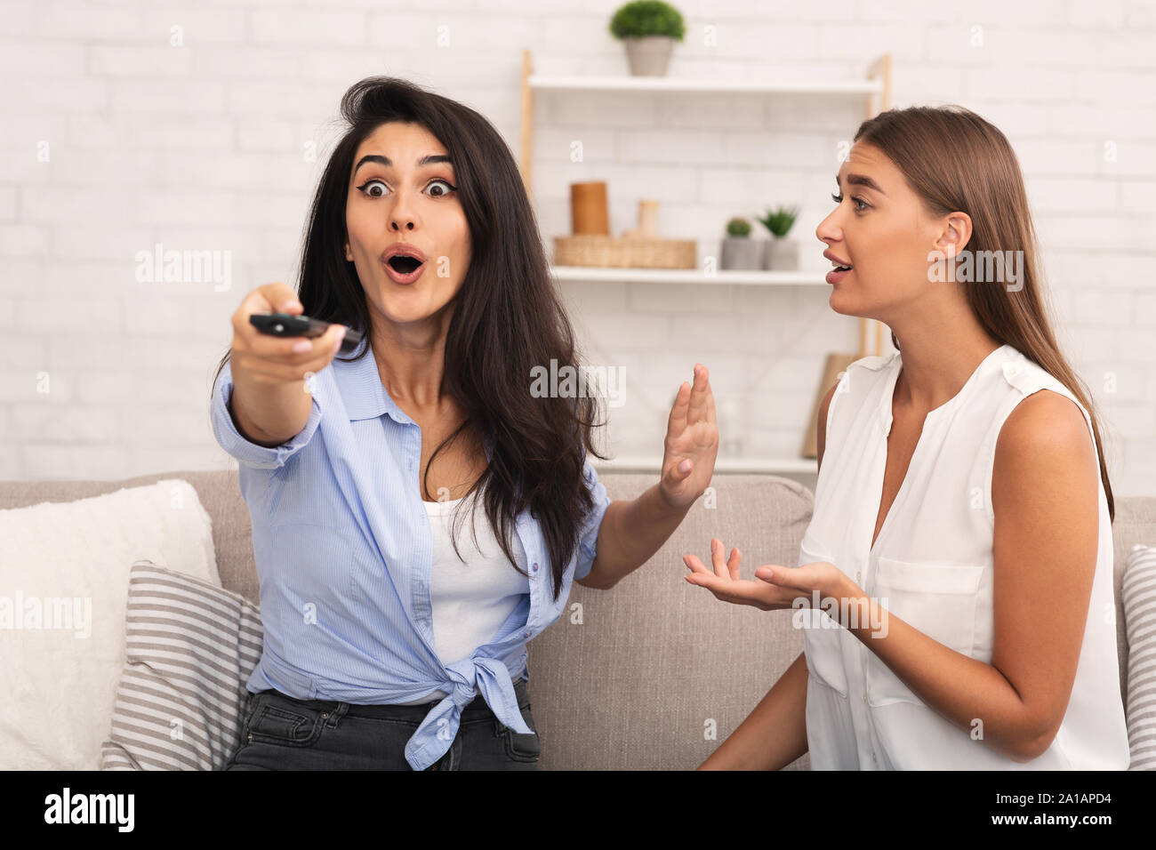 Girl Not Listening To Friend Sitting On Couch Indoor Stock Photo - Alamy
