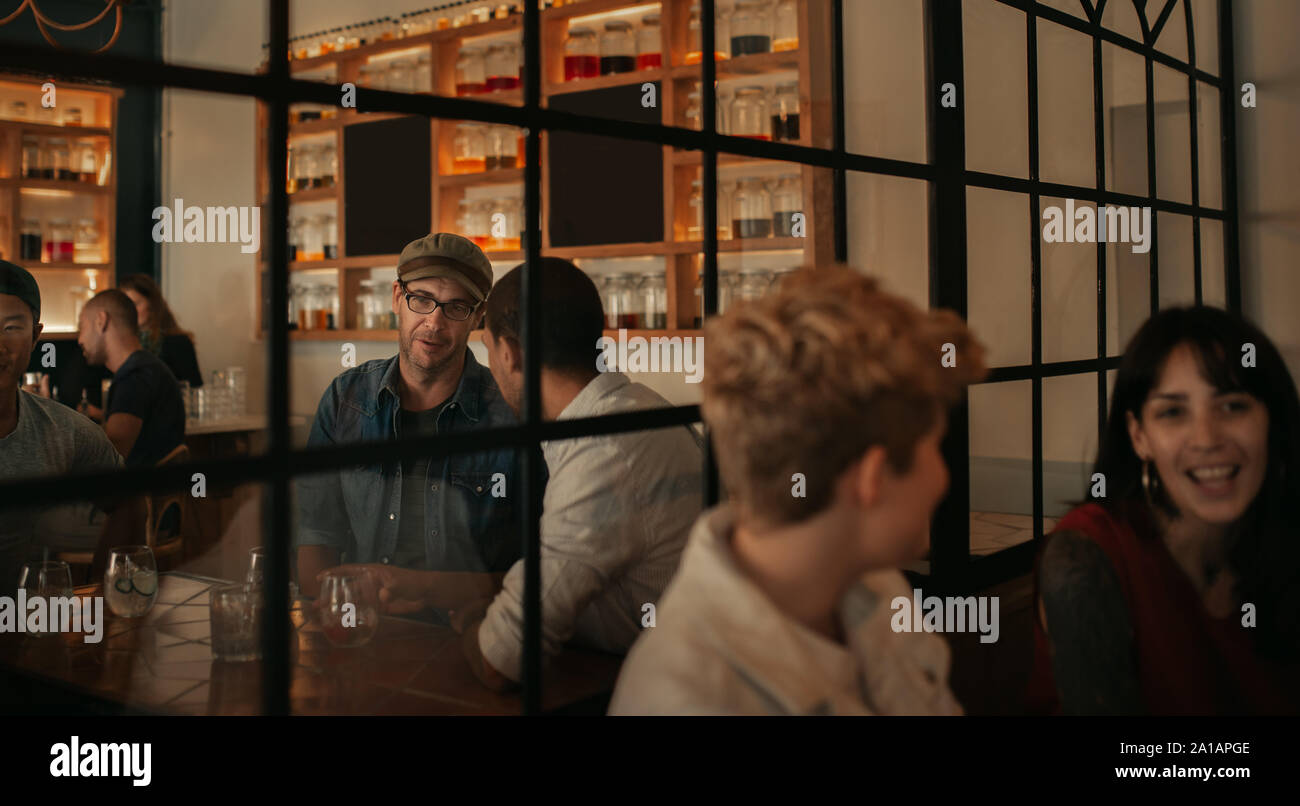Diverse people talking over drinks at a bar at night Stock Photo - Alamy