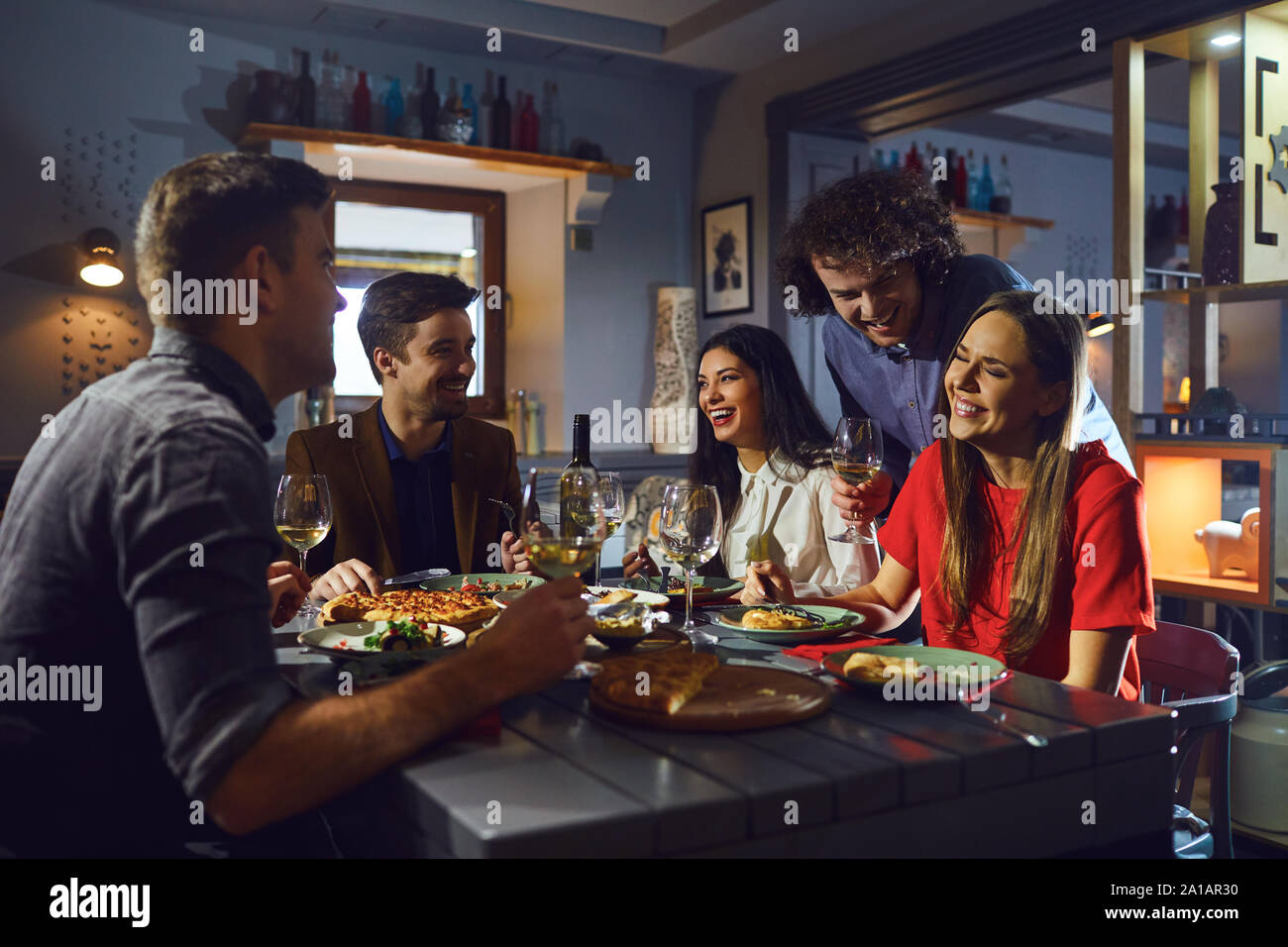 Young people meeting friends for dinner in a restaurant Stock Photo - Alamy