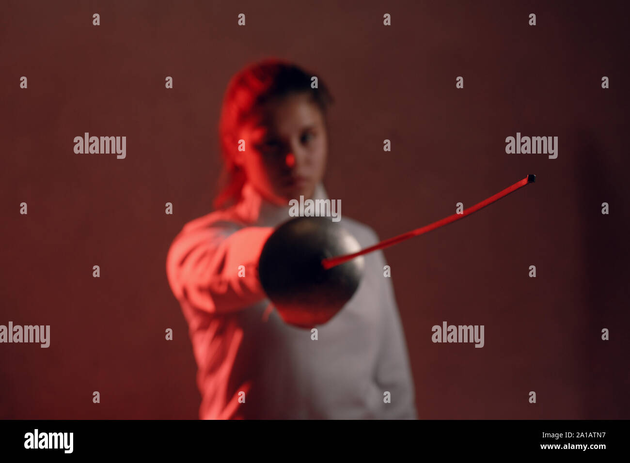 Fencer woman portrait with fencing sword in red light Stock Photo - Alamy