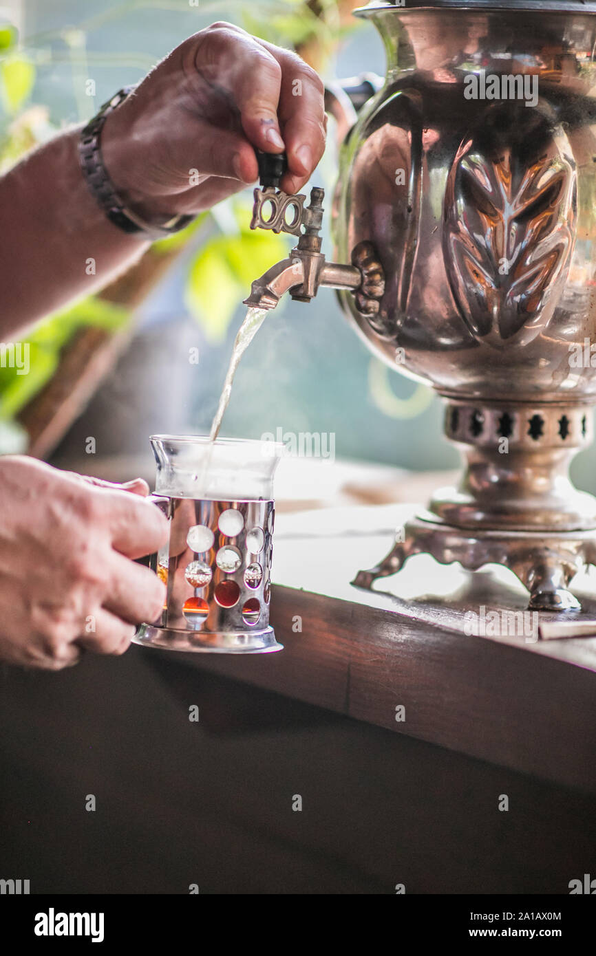 The man is pouring water from from traditional old metal russian ...