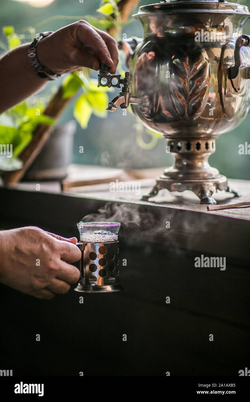 The man is pouring water from from traditional old metal russian ...