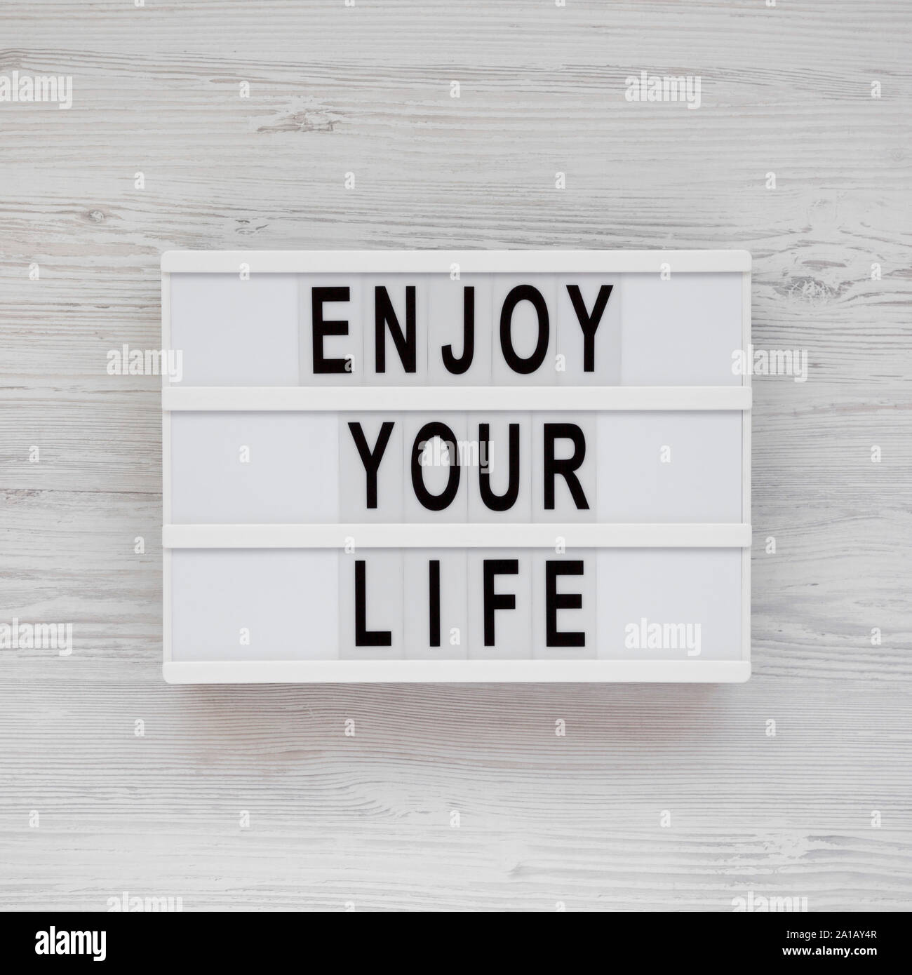 'Enjoy your life' words on a modern board over white wooden surface ...