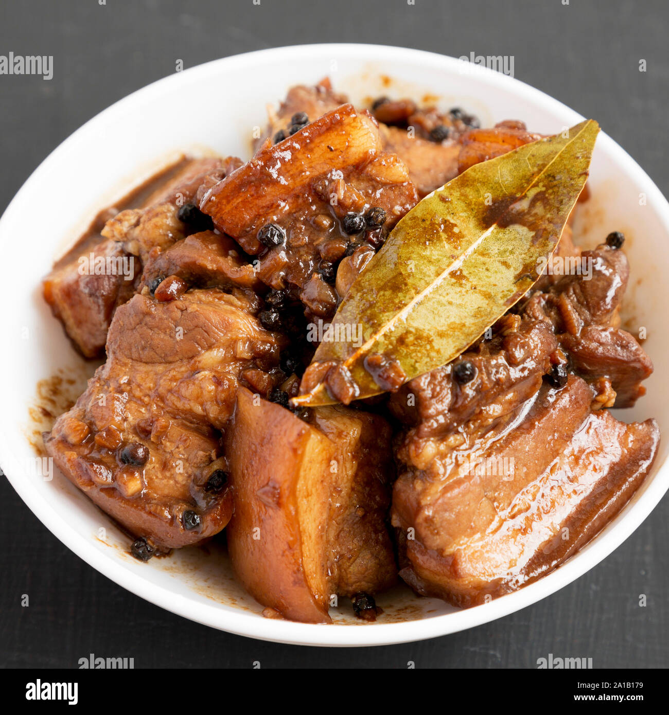 Homemade Filipino Adobo Pork in a white bowl on a black background, low ...