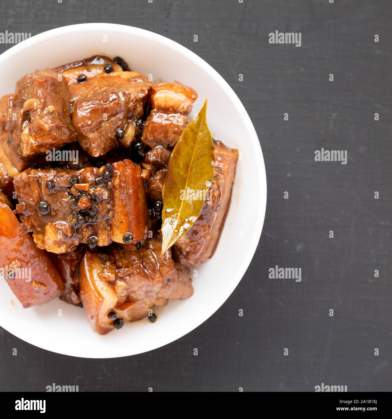 Homemade Filipino Adobo Pork in a white bowl on a black surface, top ...