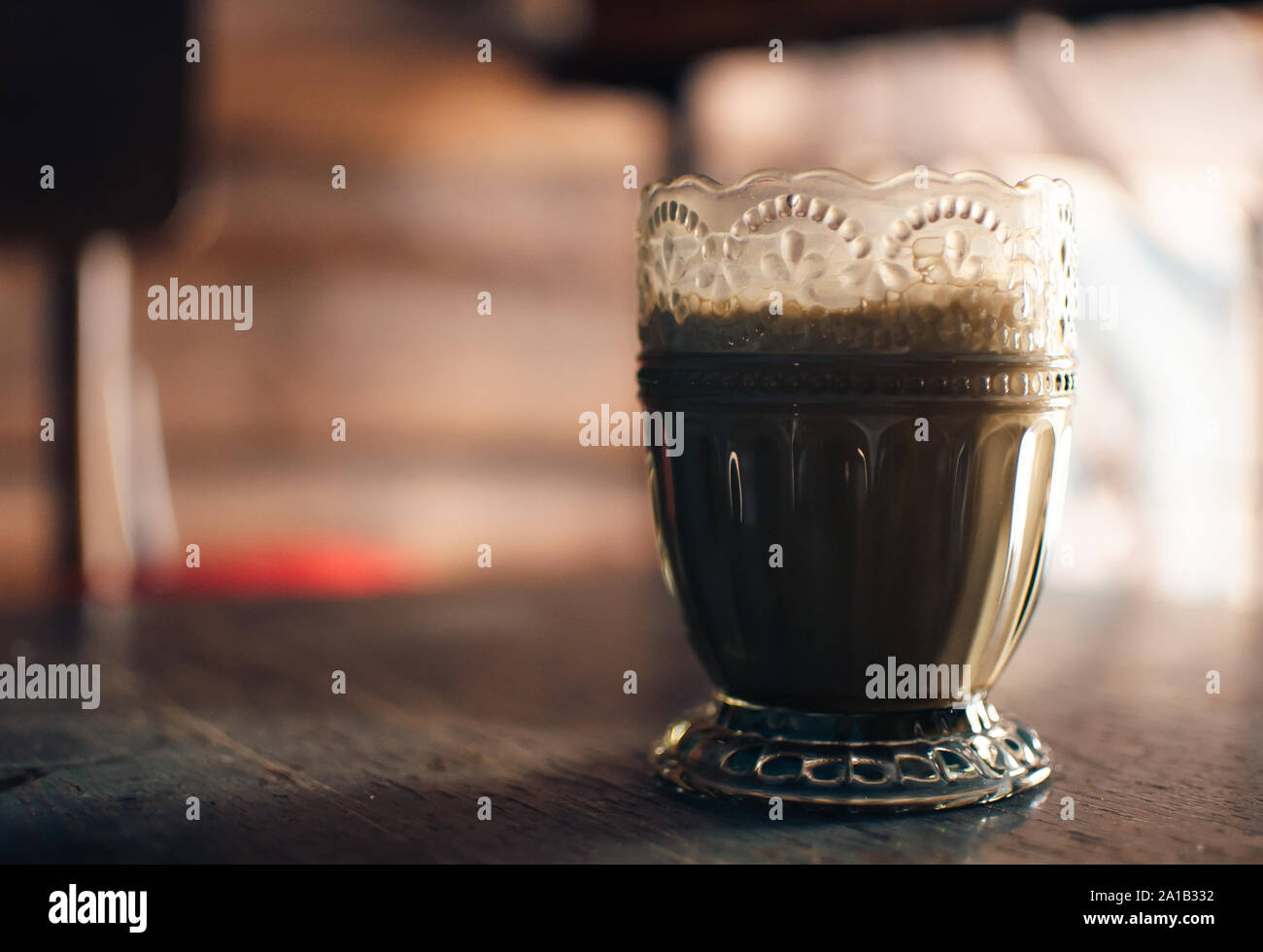 Latte coffee in an unusual glass with antique patterns. American in ...