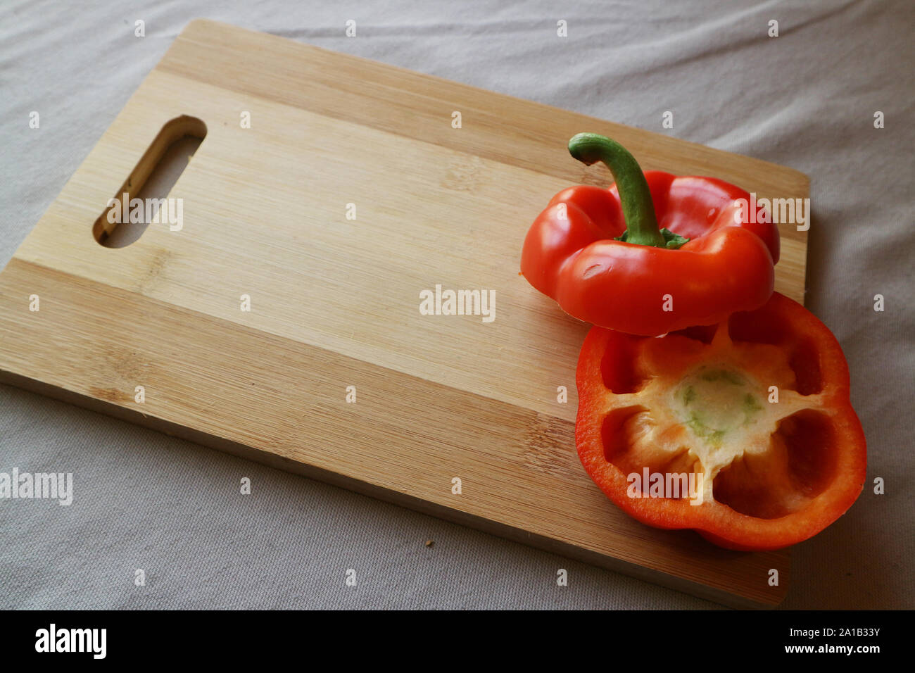 Red capsicum pepper cut in half on wood chopping board Stock Photo - Alamy