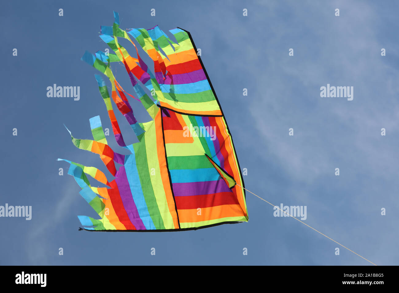 Vivid colors of a big kite flying on the blue sky Stock Photo - Alamy